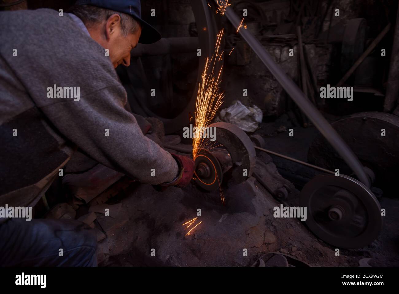 the blacksmith polishing metal products making sparks while using a ...