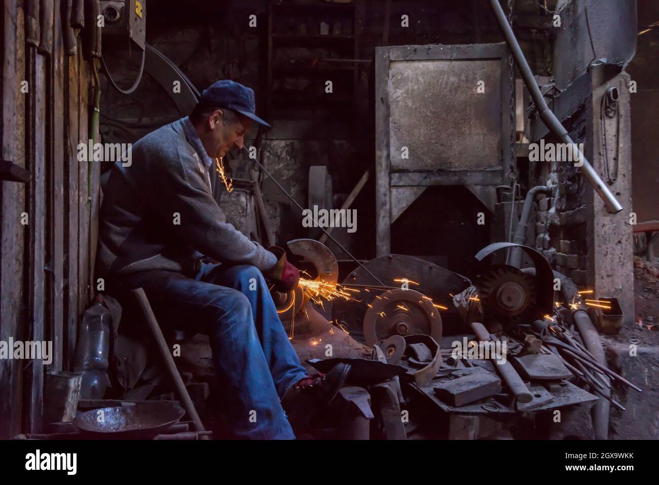 the blacksmith polishing metal products making sparks while using a ...