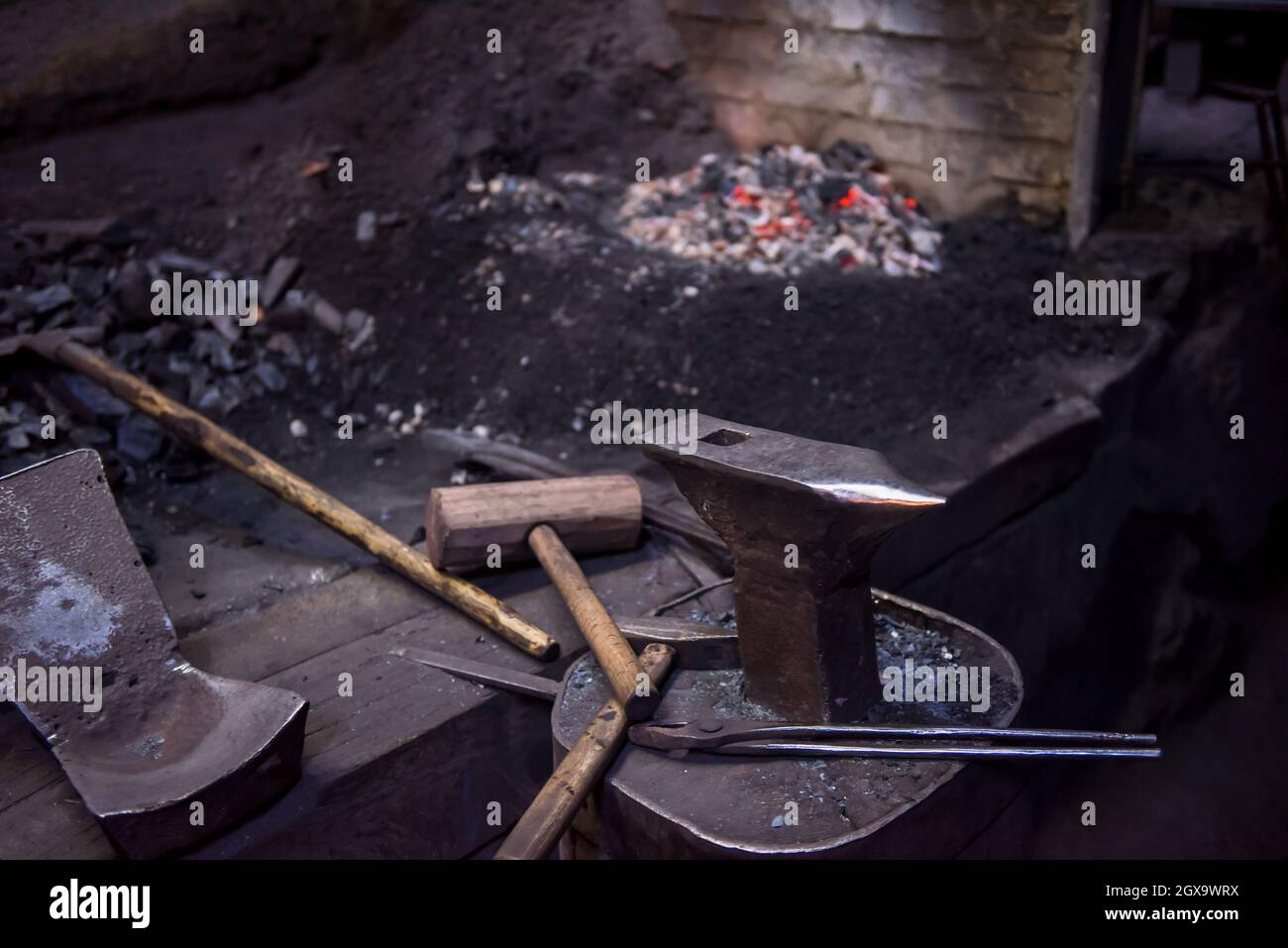 Working tool forge consisting of the anvil, hammer and tongs at blacksmith traditional workshop ...