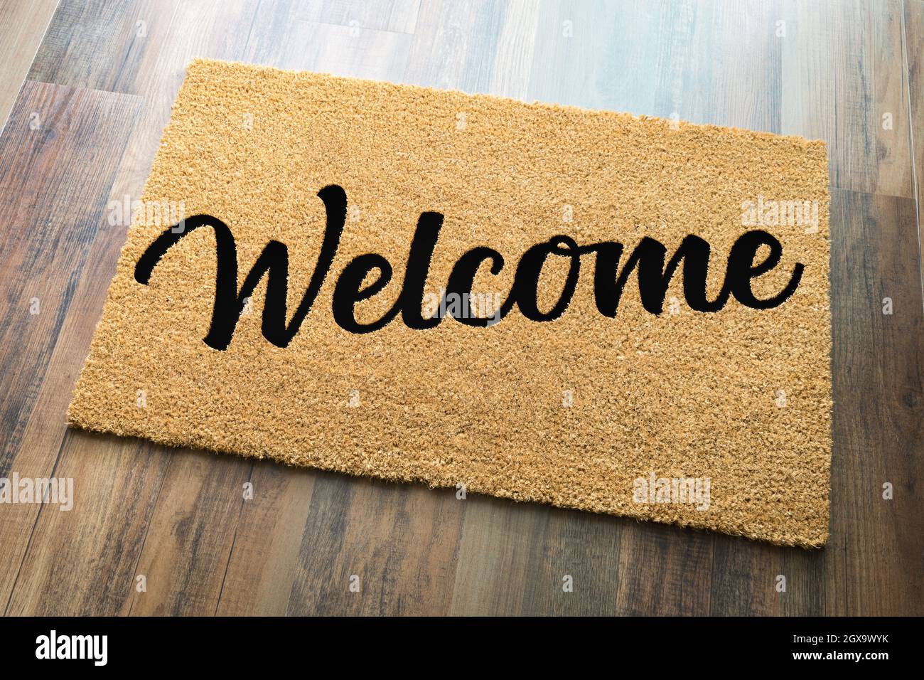 Tan Welcome Mat On Wood Floor Background Stock Photo - Alamy