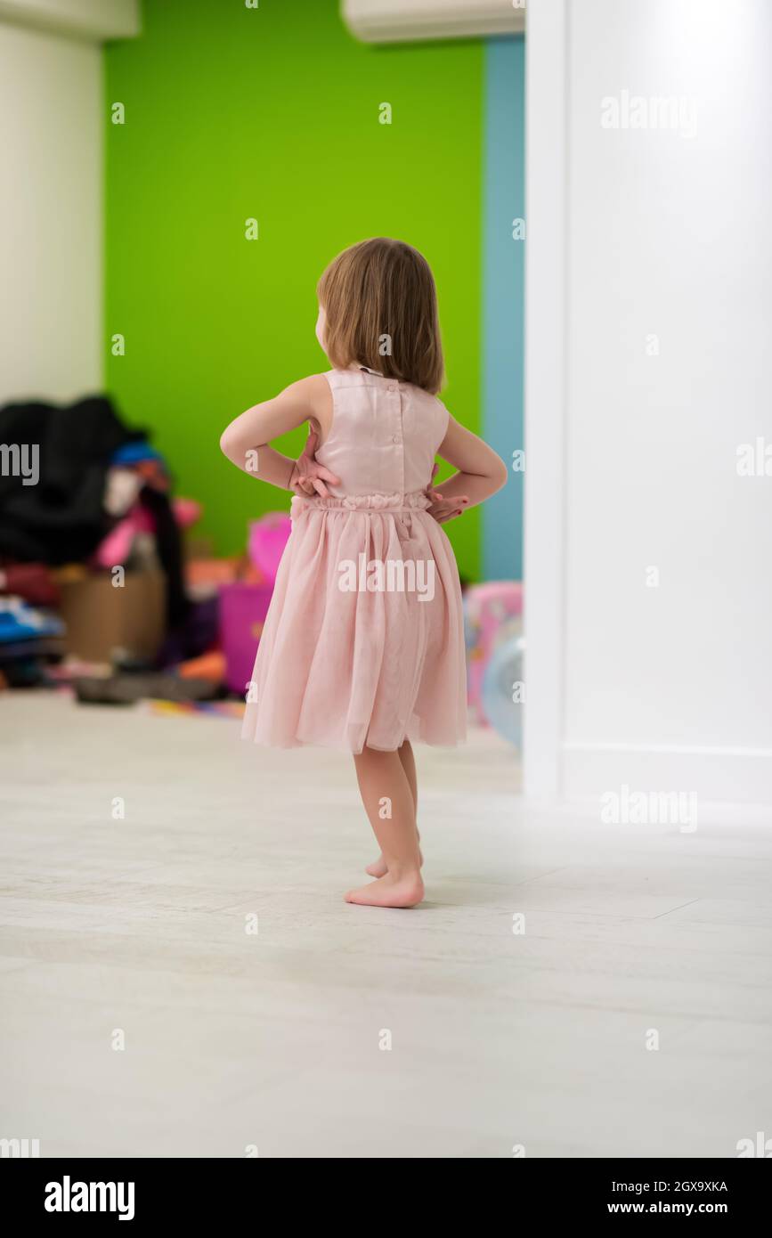 rear view of happy cute little girl in pink dress enjoying while ...