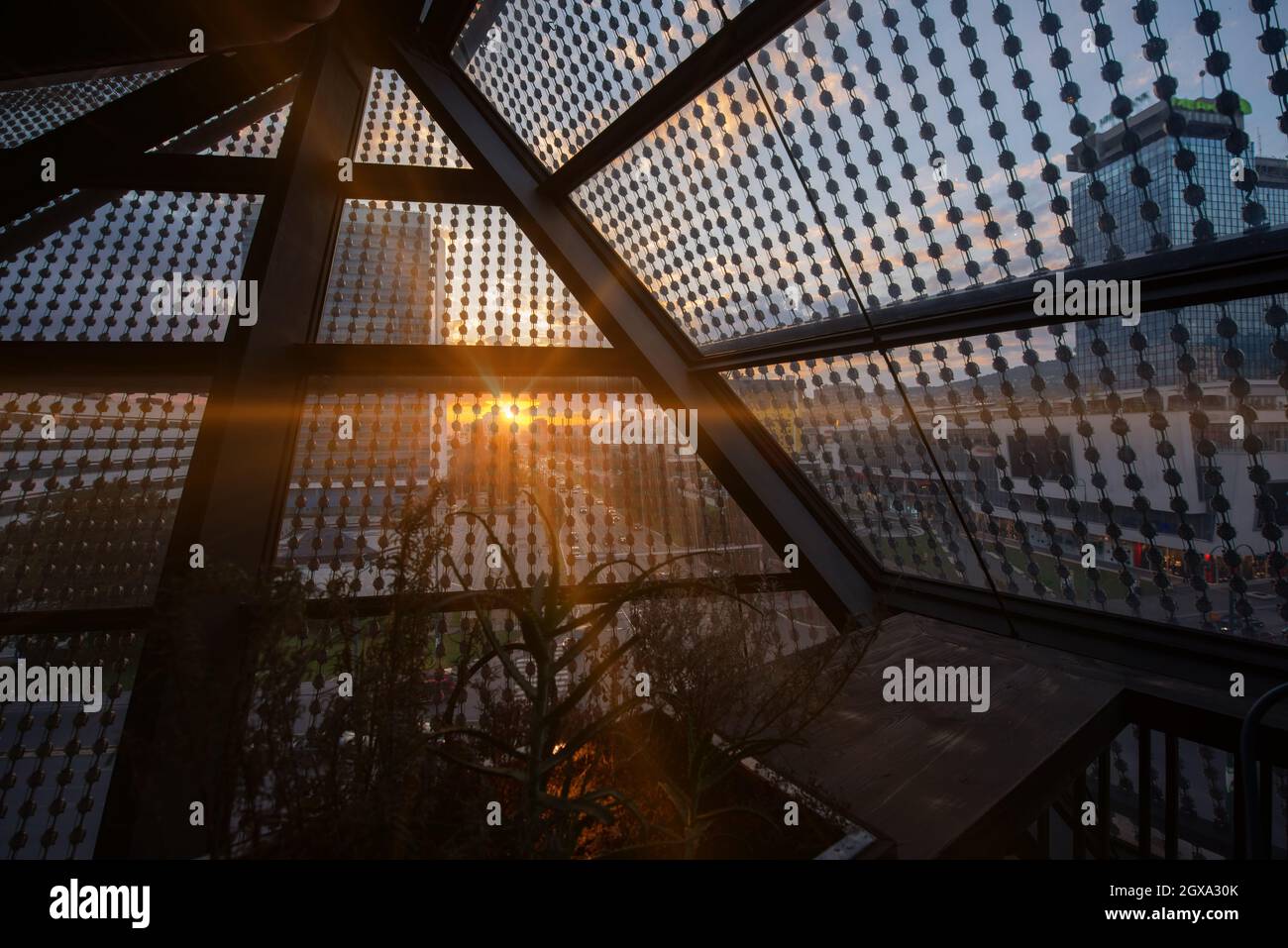 sunset or sunrise above the city through a glass roof in a modern ...