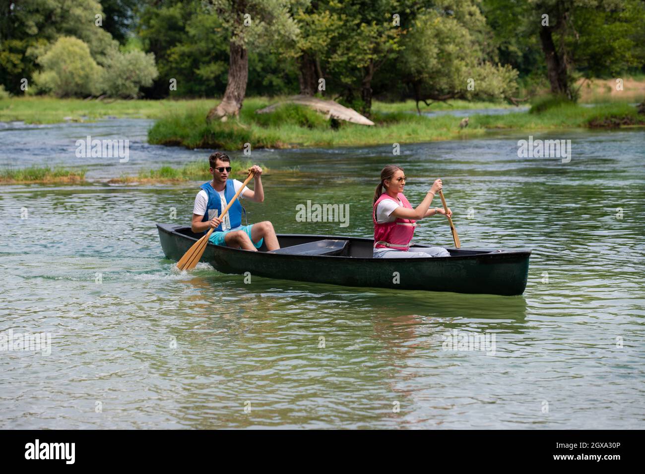 Couple friends are canoeing in a wild river surrounded by the beautiful ...