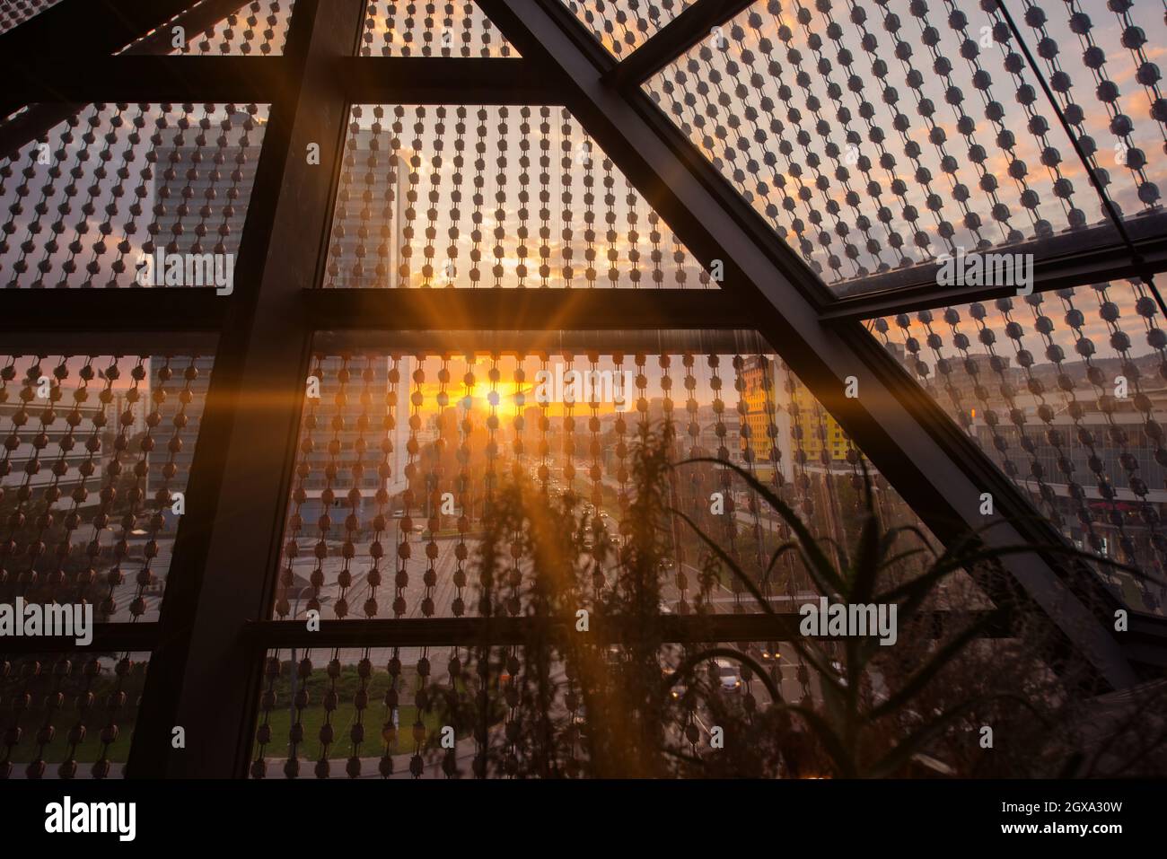 sunset or sunrise above the city through a glass roof in a modern ...