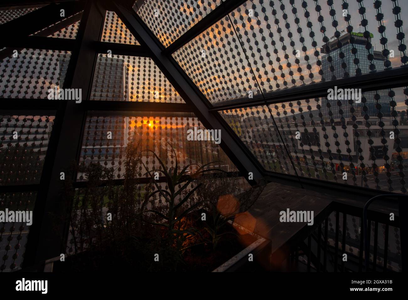 sunset or sunrise above the city through a glass roof in a modern ...