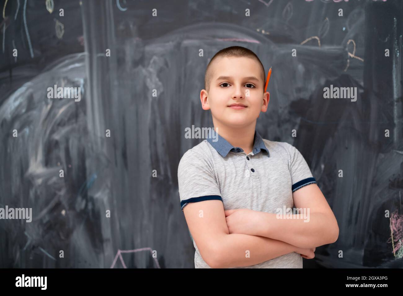portrait of happy boy with orange wooden pen behind the ear standing in ...