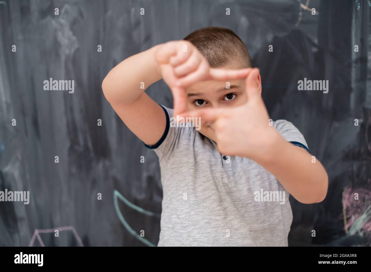 happy cute little boy having fun making hand frame gesture while ...
