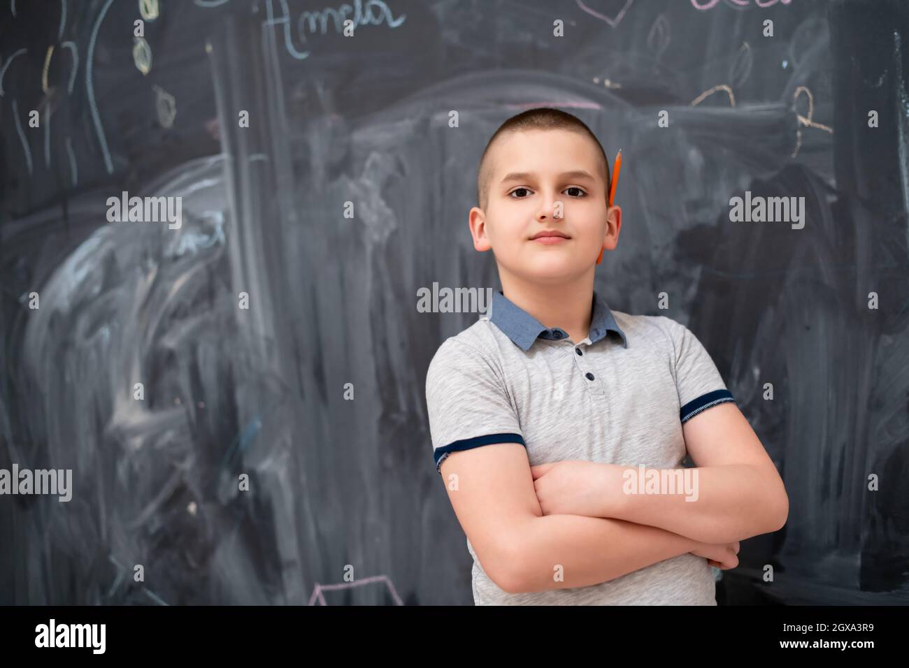 portrait of happy boy with orange wooden pen behind the ear standing in ...
