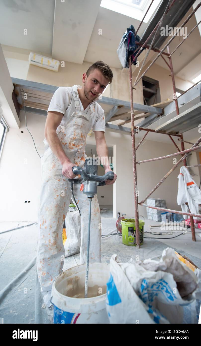 professional Male builder mixing plaster in bucket using electric mixer ...