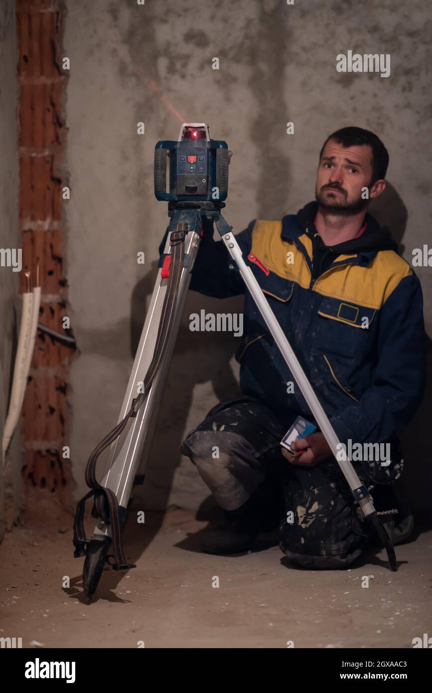 professional worker using laser level in a building under construction ...