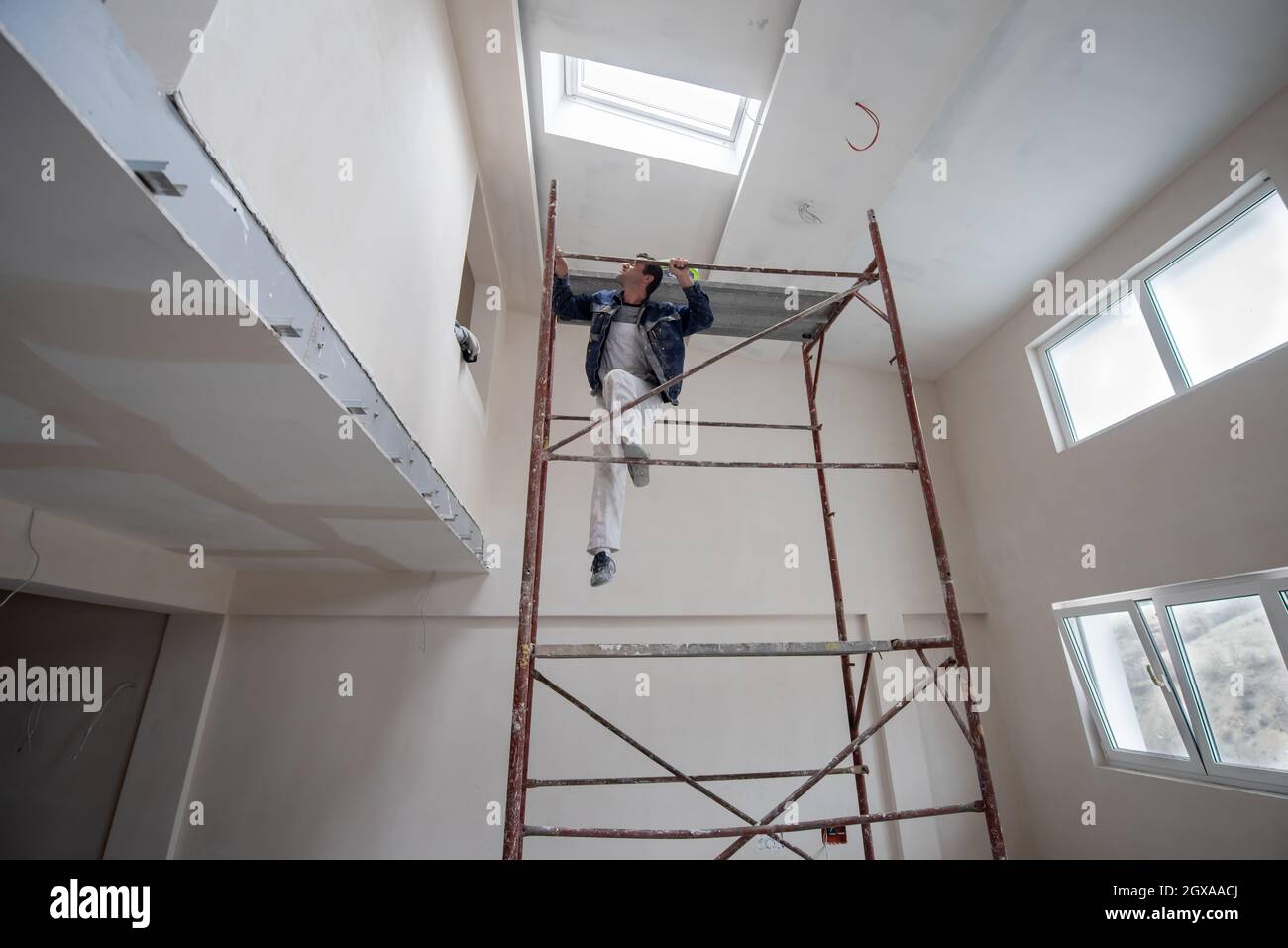 young professional construction worker using scaffold while plastering ...