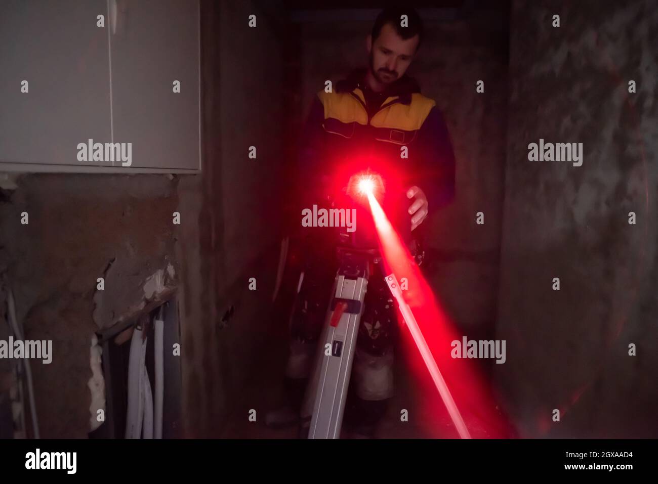 professional worker using laser level in a building under construction ...
