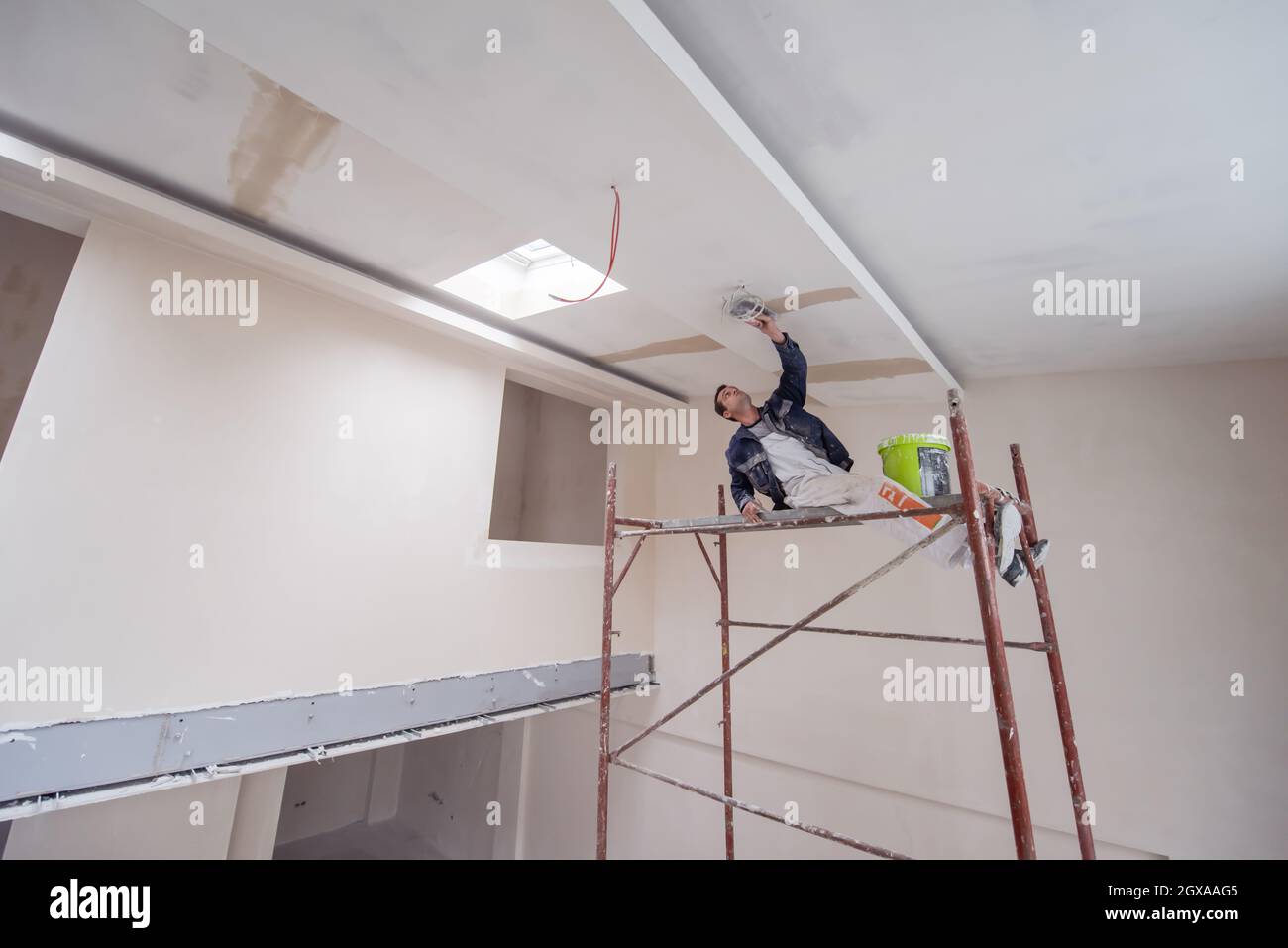 young professional construction worker using scaffold while plastering ...