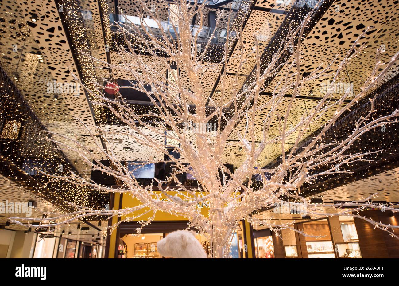 Glowing white tree made of wire and light bulbs in big modern shopping ...