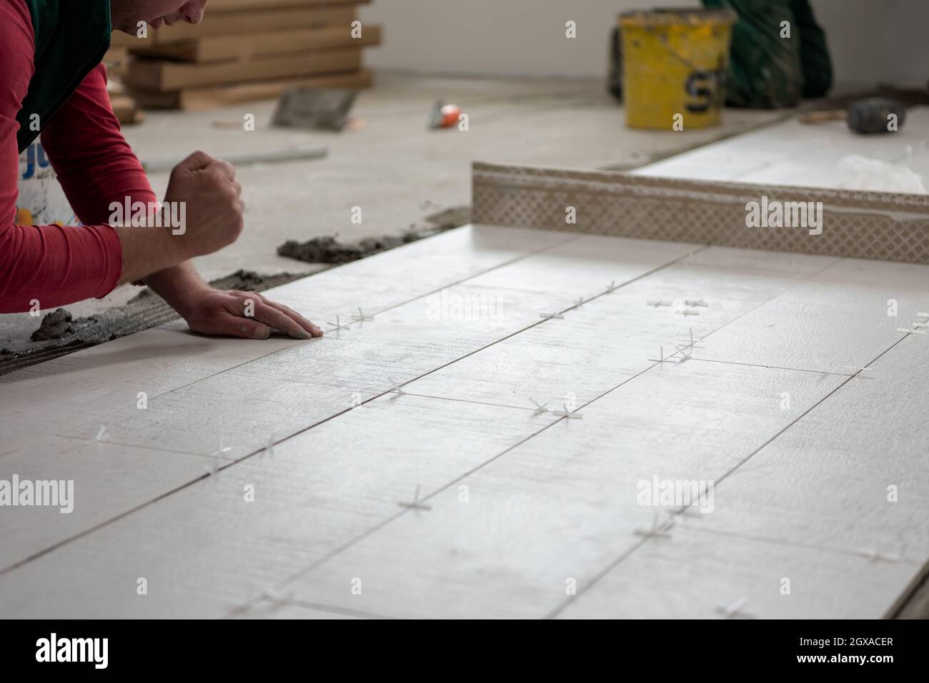 skilled worker installing the ceramic wood effect tiles on the floor ...