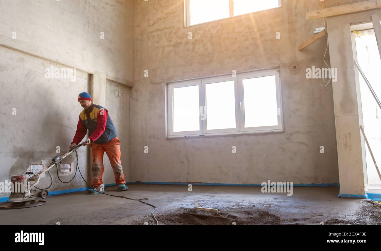 Laborer performing and polishing sand and cement screed floor on the ...