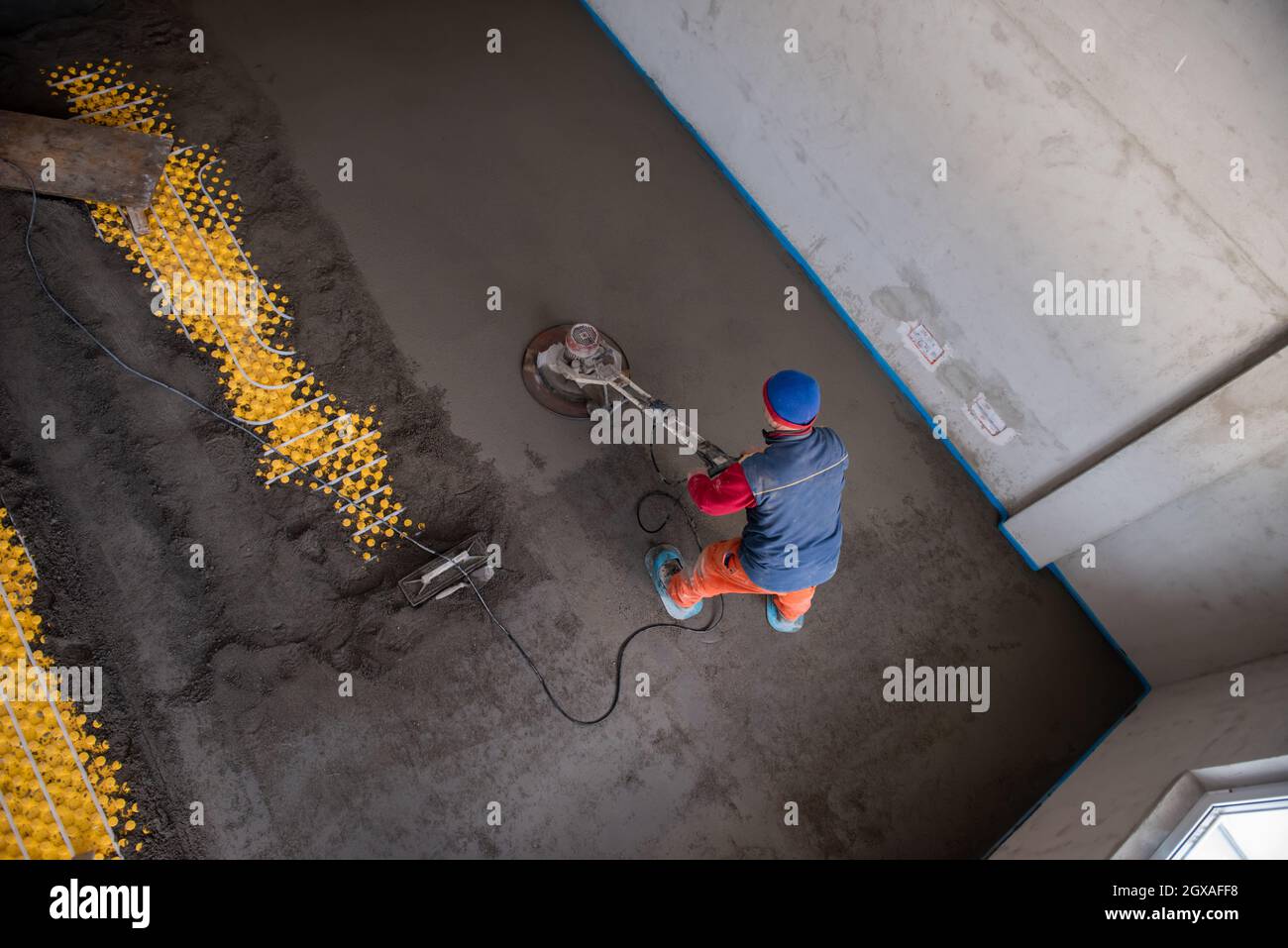 Laborer performing and polishing sand and cement screed floor on the ...