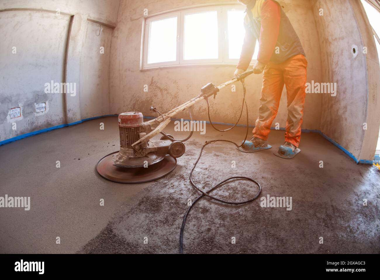 Laborer performing and polishing sand and cement screed floor on the ...