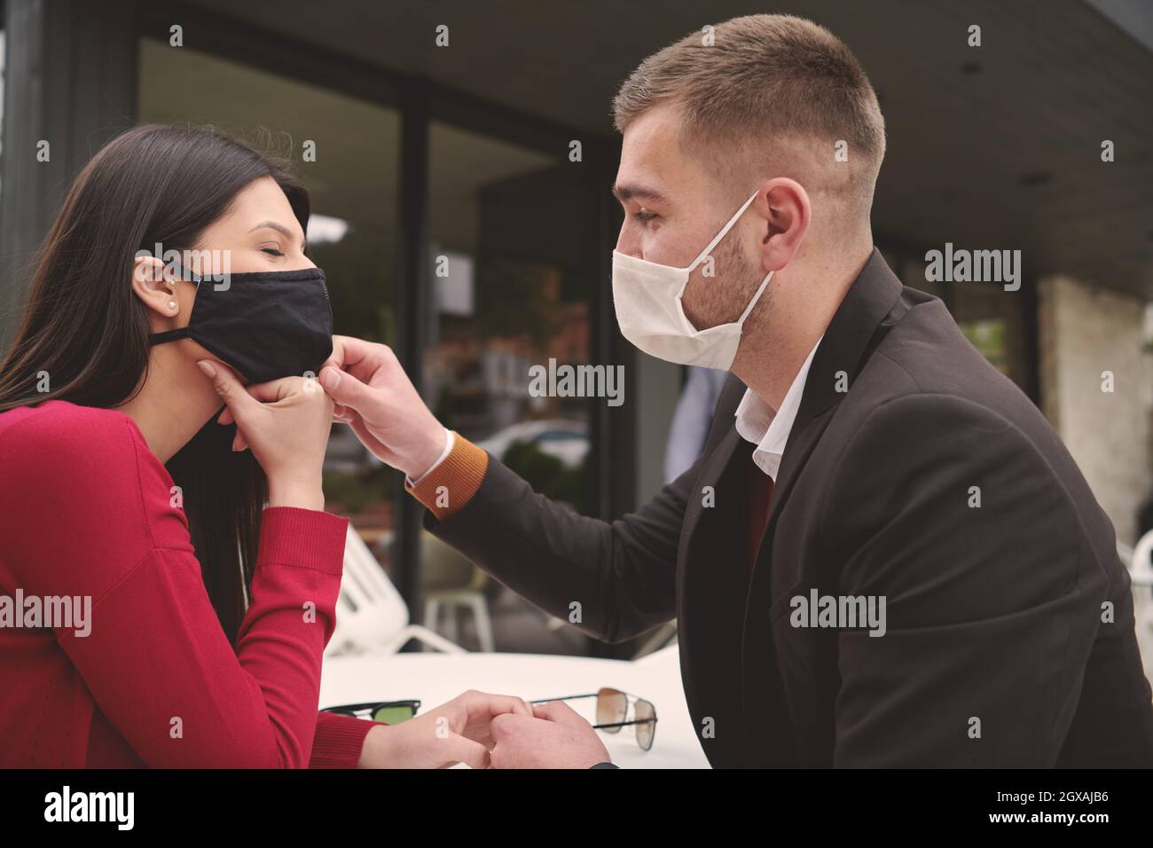 couple with protective medical mask having coffee break in a restaurant ...