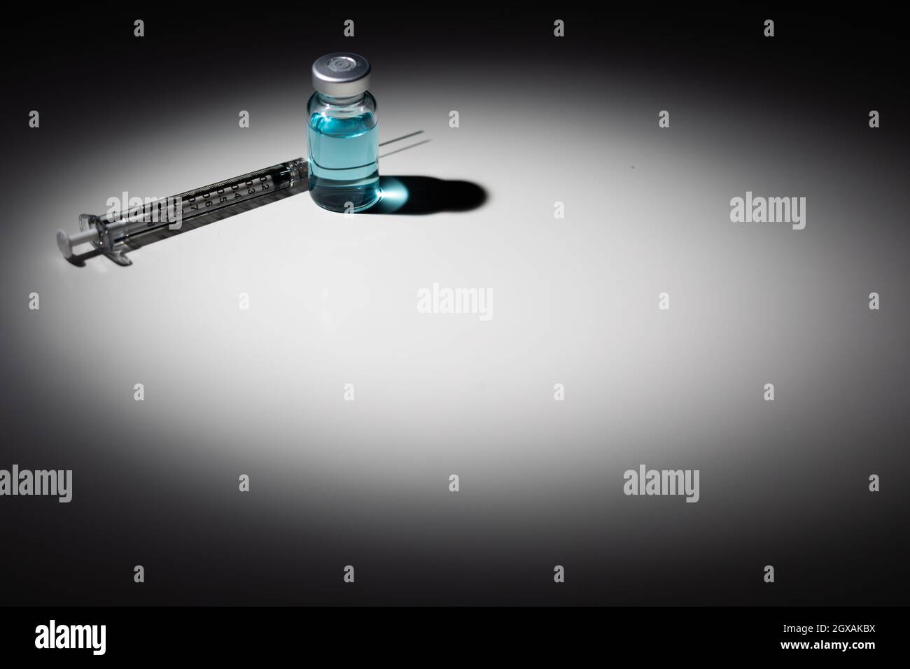 Syringe Needle and Medicine Vial With Light Blue Chemical Spot Lit on ...