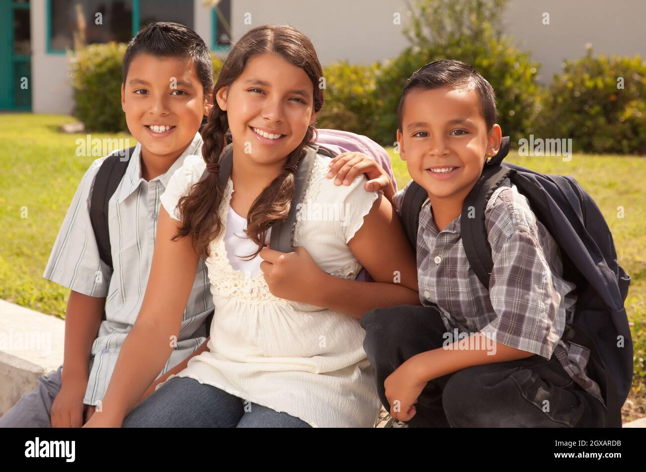 Young Hispanic Student Children Wearing Backpacks On School Campus ...