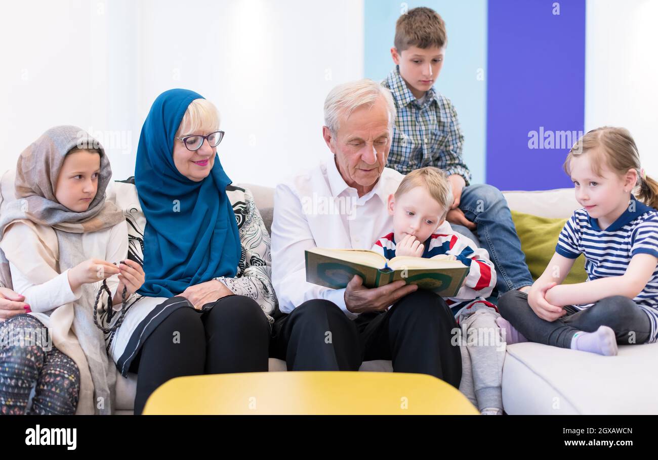modern muslim family grandparents with grandchildren reading Quran and ...
