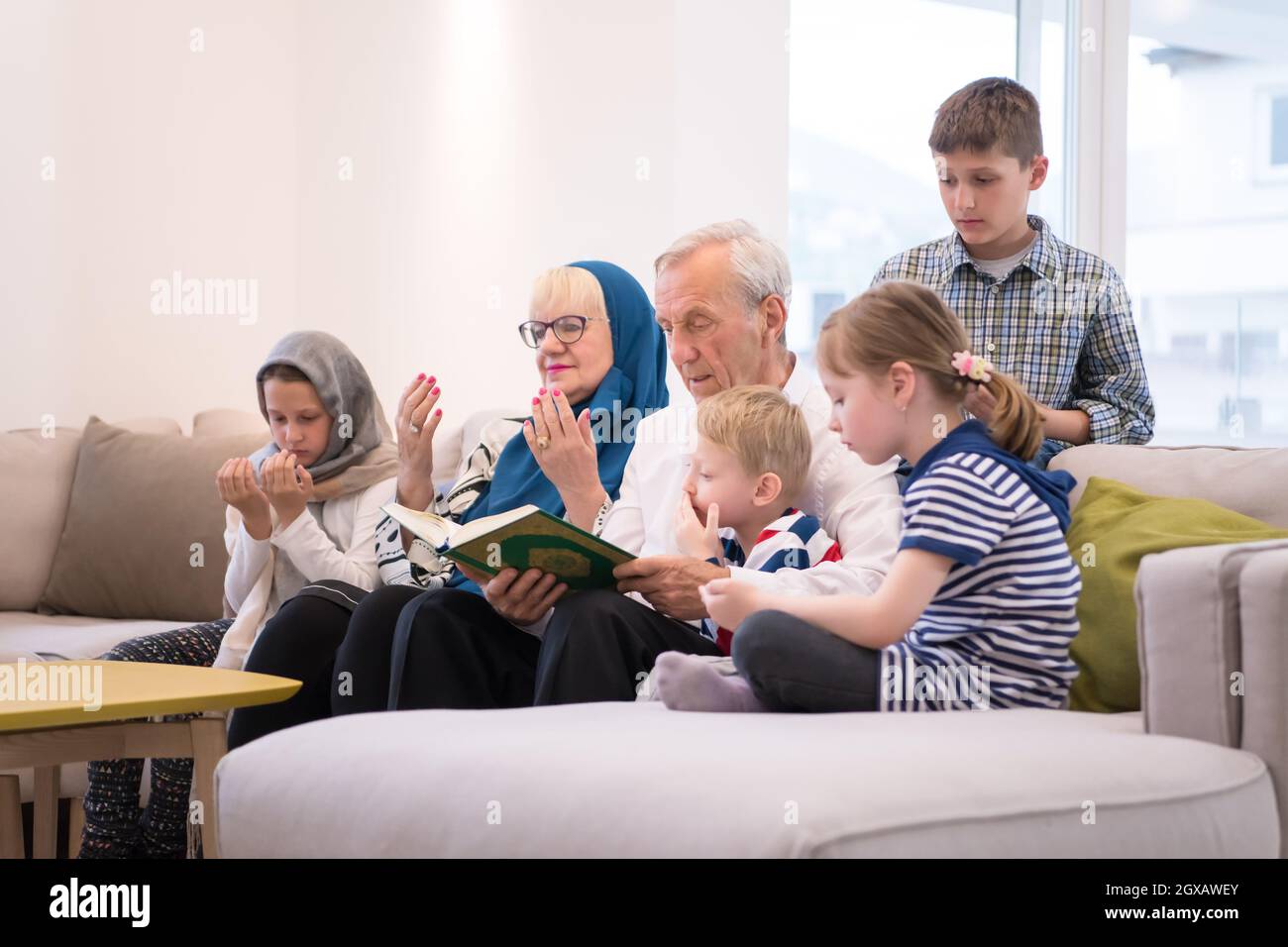 modern muslim family grandparents with grandchildren reading Quran and ...