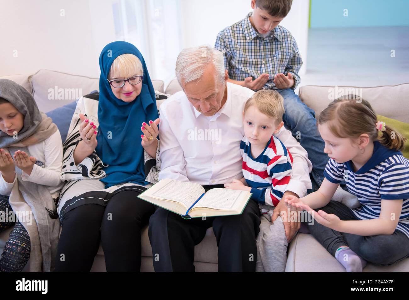 modern muslim family grandparents with grandchildren reading Quran and ...