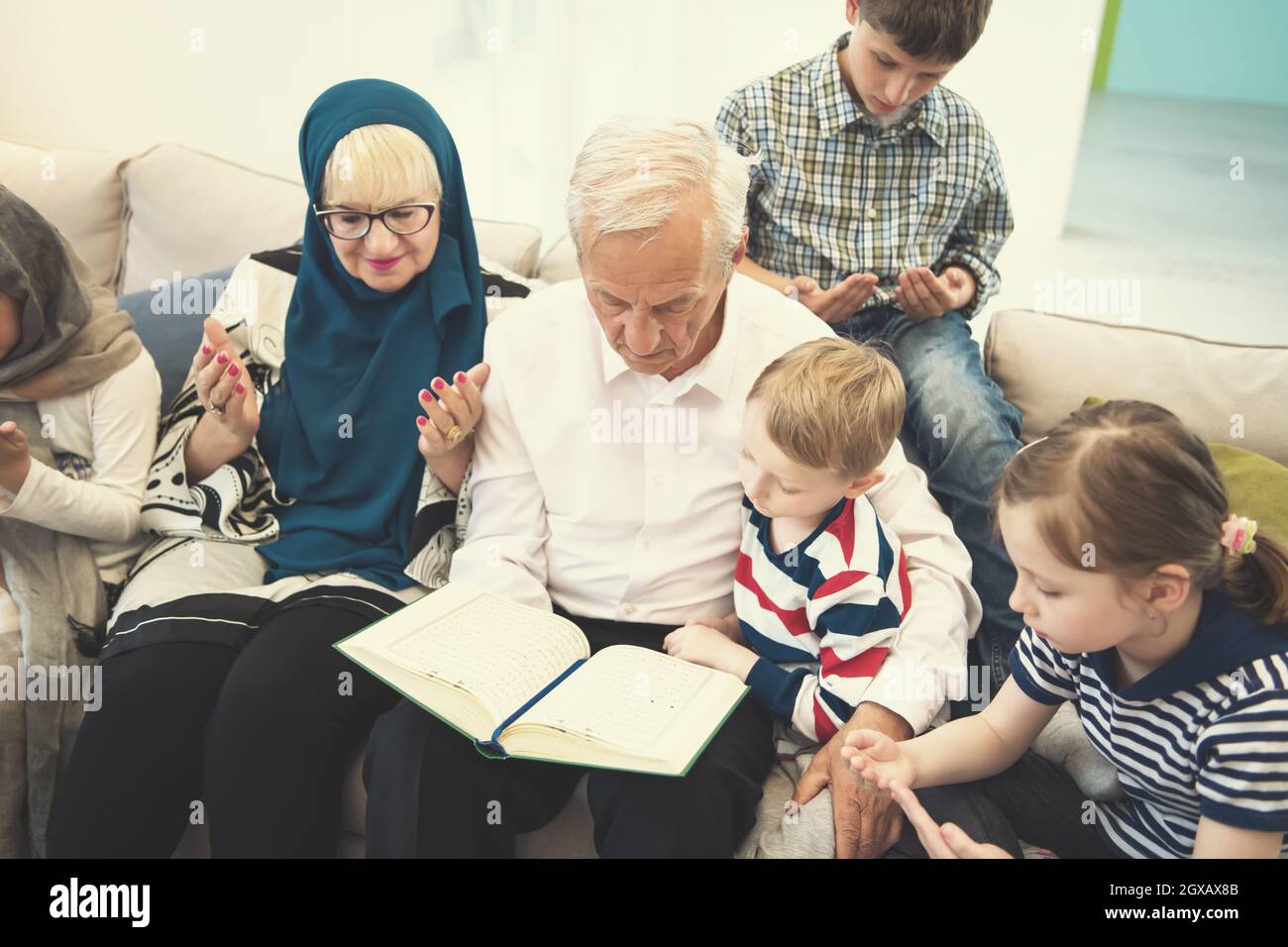modern muslim family grandparents with grandchildren reading Quran and ...