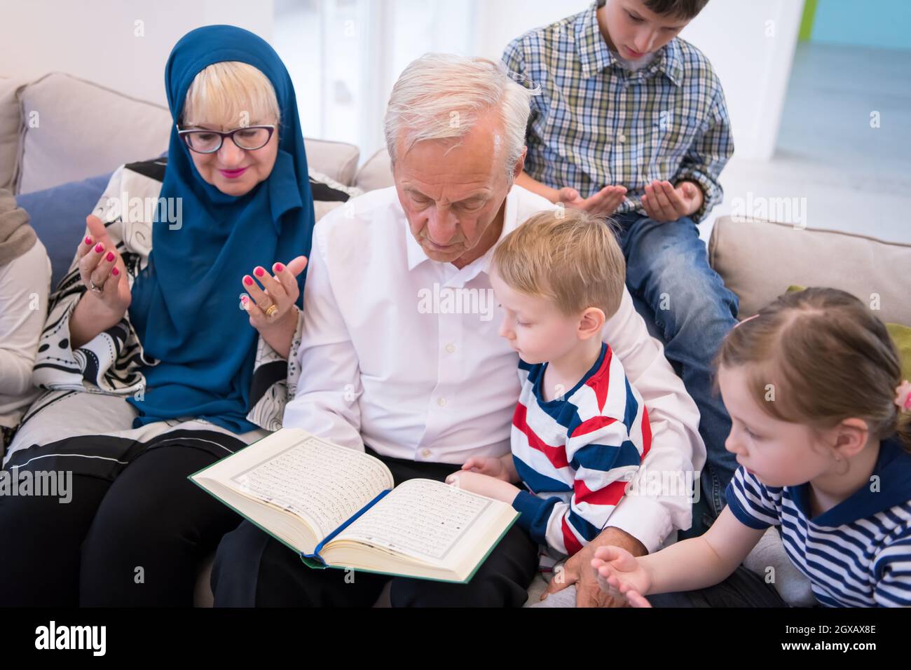 modern muslim family grandparents with grandchildren reading Quran and ...