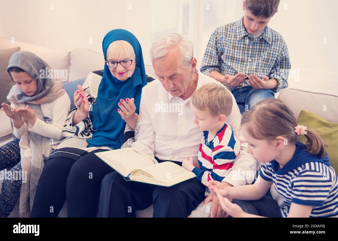 modern muslim family grandparents with grandchildren reading Quran and ...