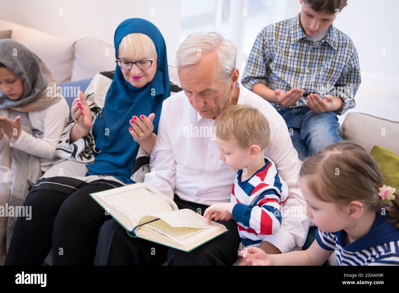 modern muslim family grandparents with grandchildren reading Quran and ...