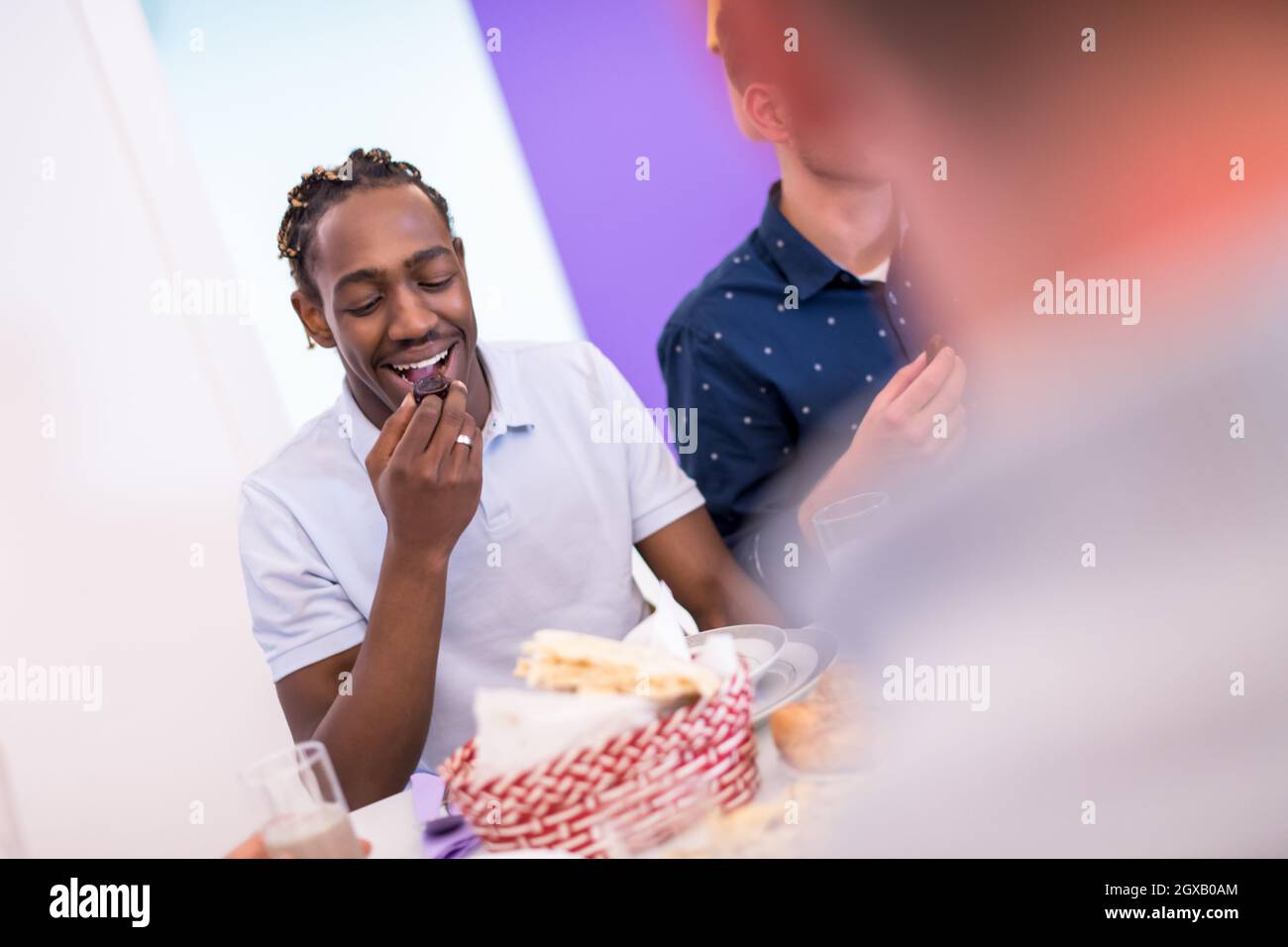 young african american man eating dates with modern multiethnic muslim ...