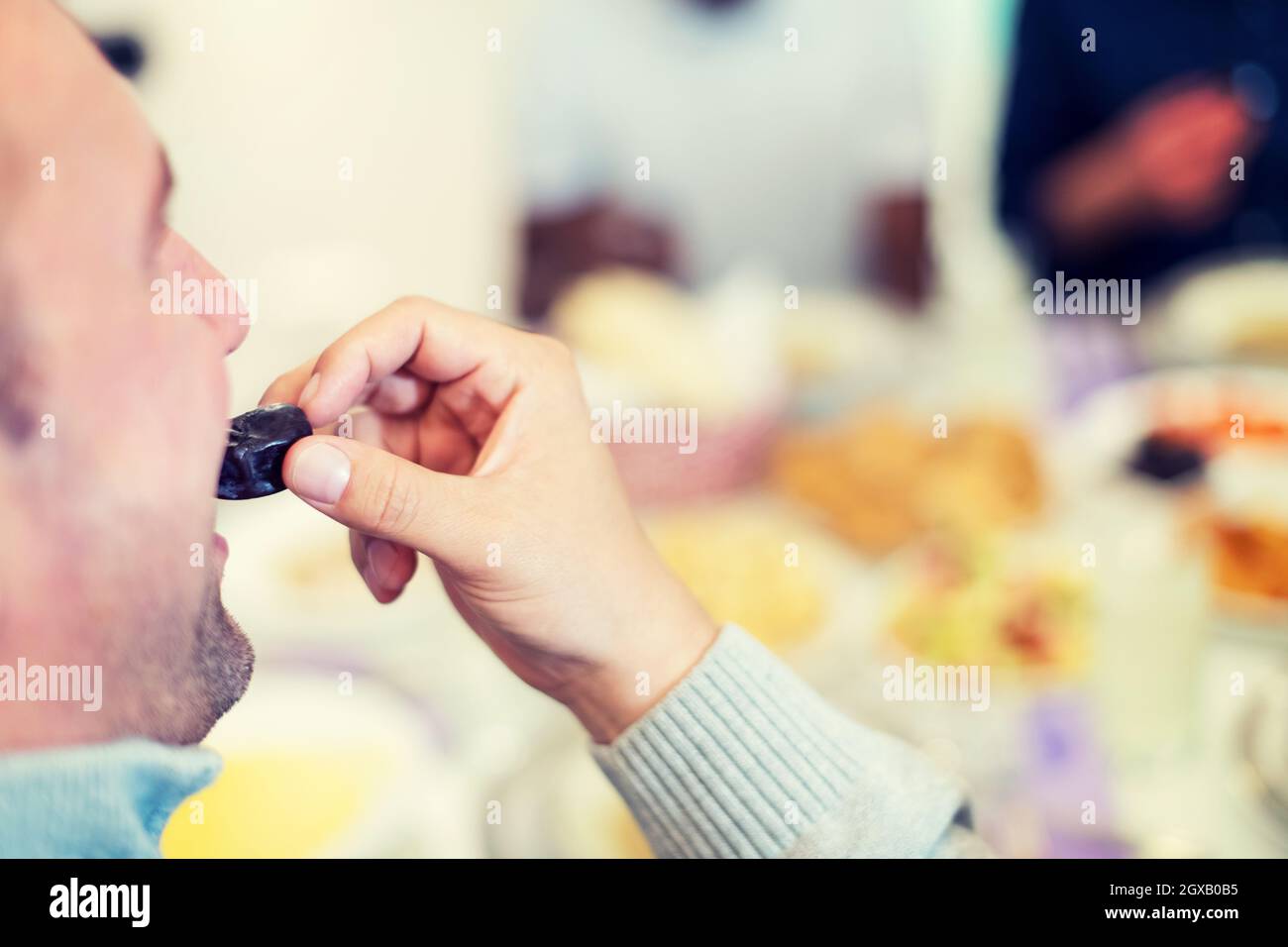 young man eating dates with modern multiethnic muslim family while ...