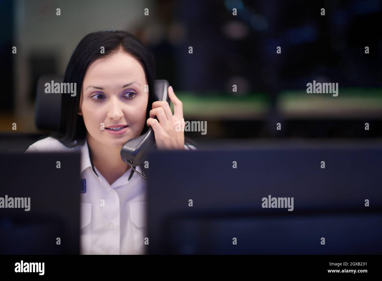 Female security guard operator talking on the phone while working at ...