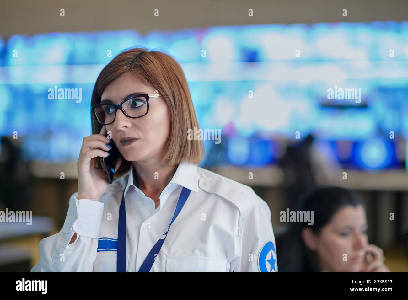 Female security guard operator talking on the phone while working at ...