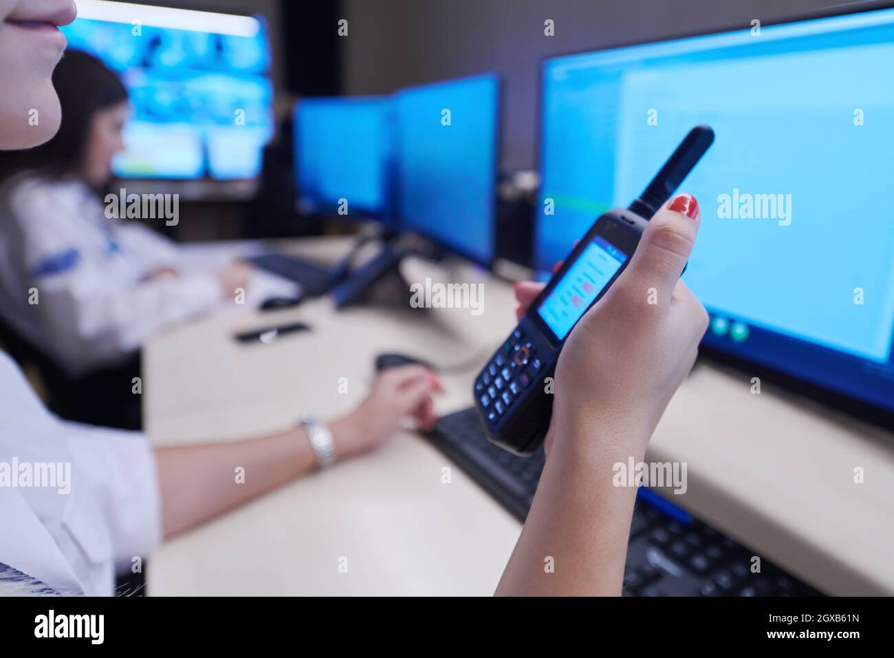 Female security operator holding portable radio in hand while working ...
