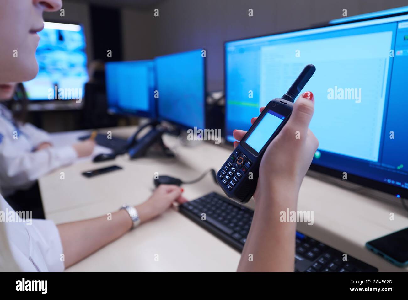 Female security operator holding portable radio in hand while working ...