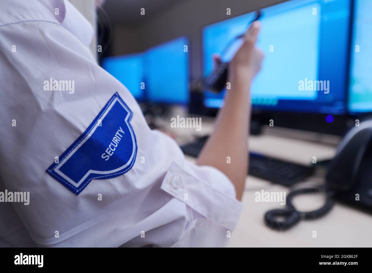Female security operator holding portable radio in hand while working ...