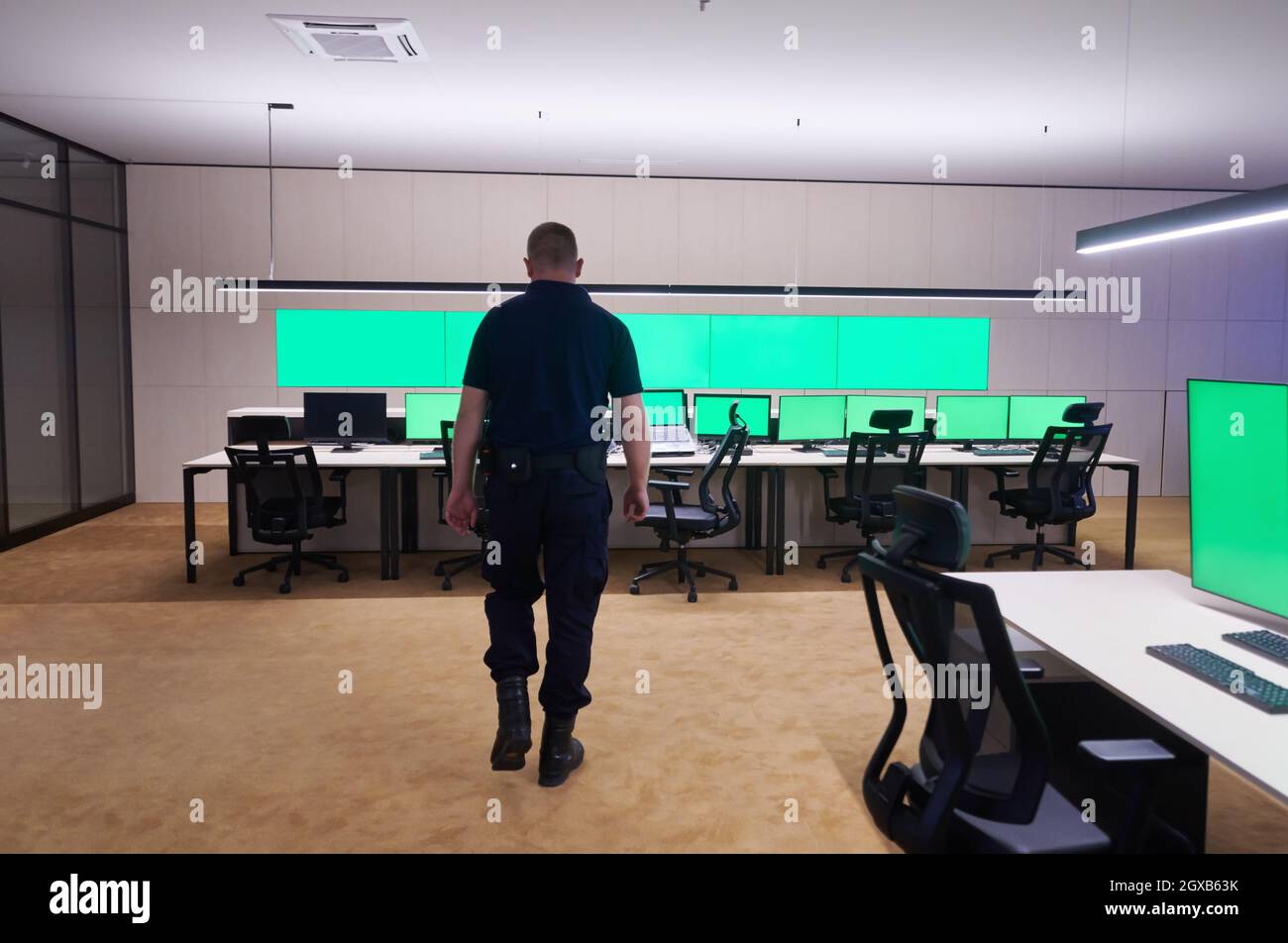 young male security operator walking through data system control room ...
