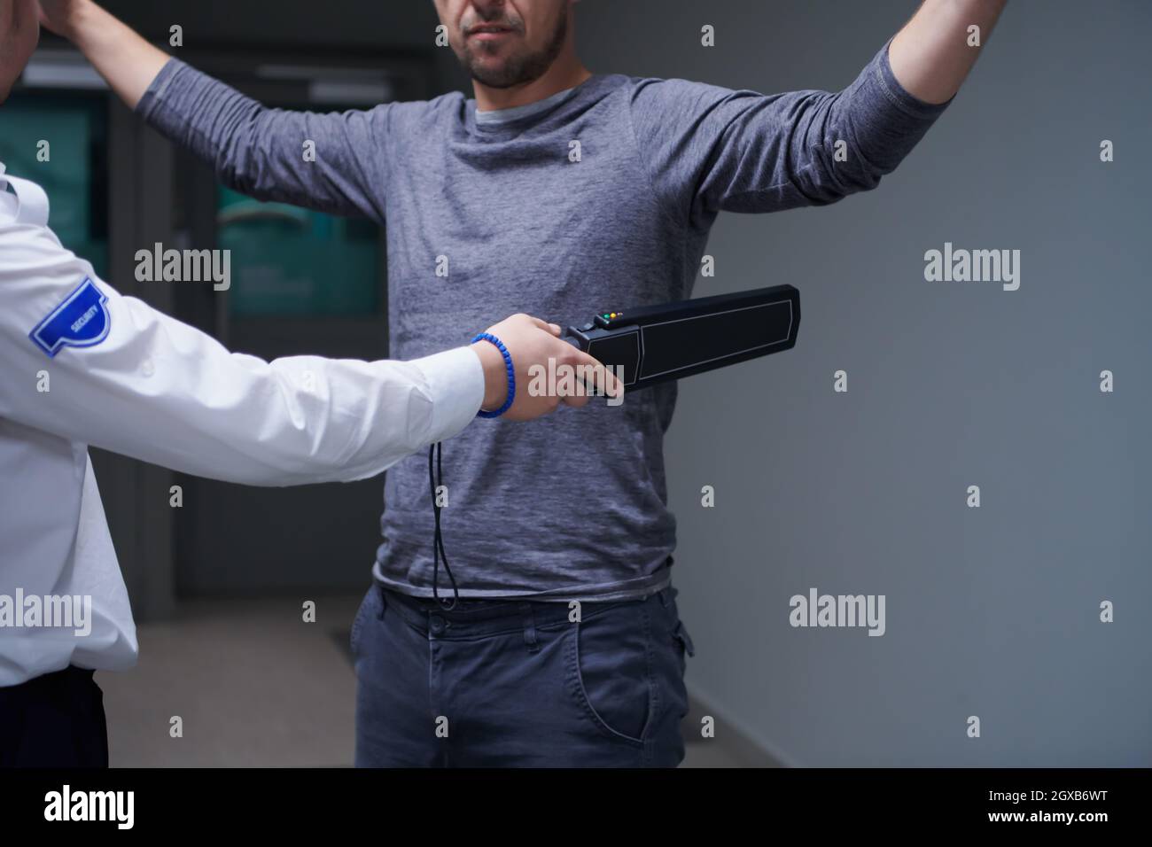 Security guard making body searching procedure with a metal detector on ...
