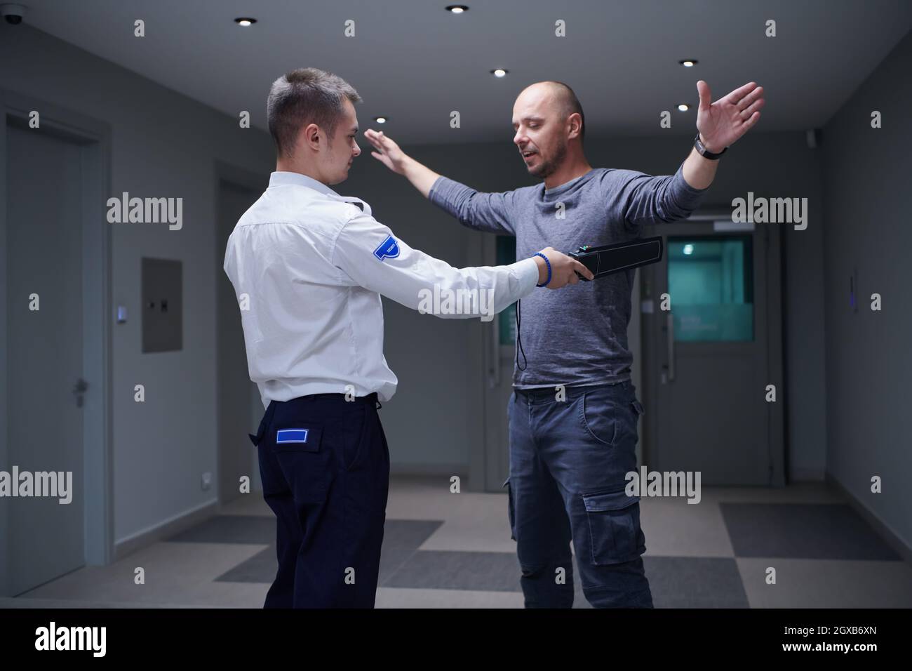 Security guard making body searching procedure with a metal detector on ...