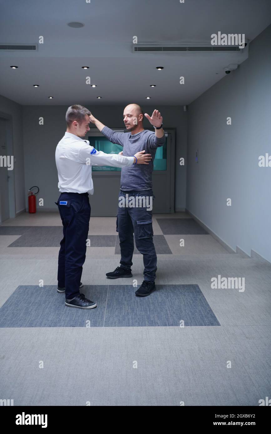 Security guard making body searching procedure on man for finding ...