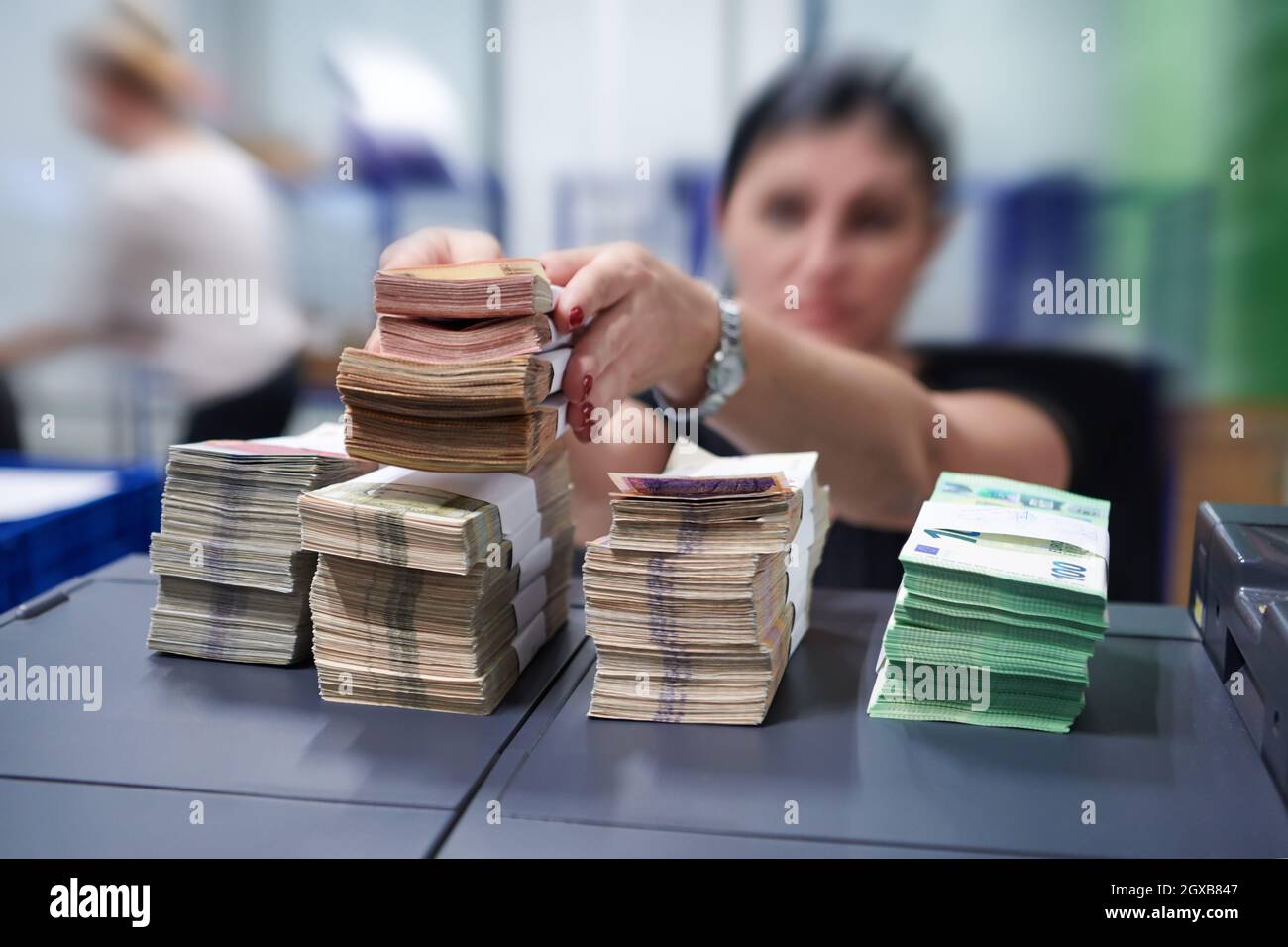 Bank employees using money counting machine while sorting and counting ...