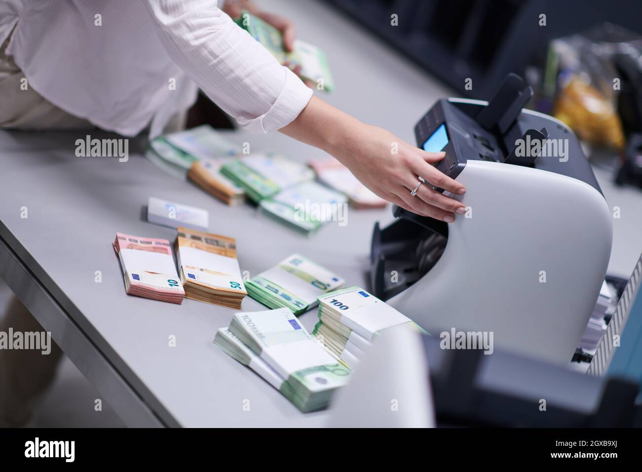Bank employees using money counting machine while sorting and counting ...