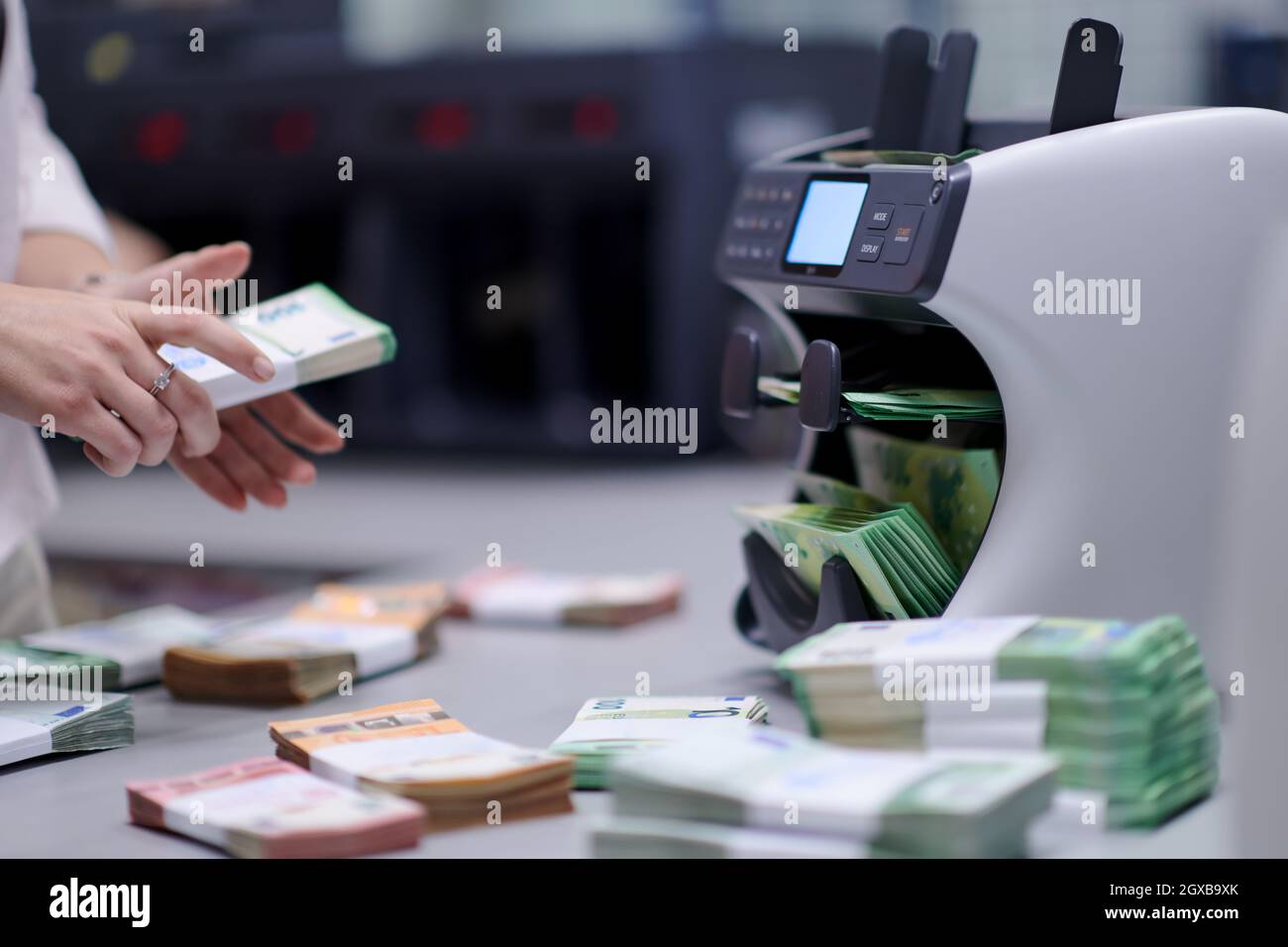 Bank employees using money counting machine while sorting and counting ...