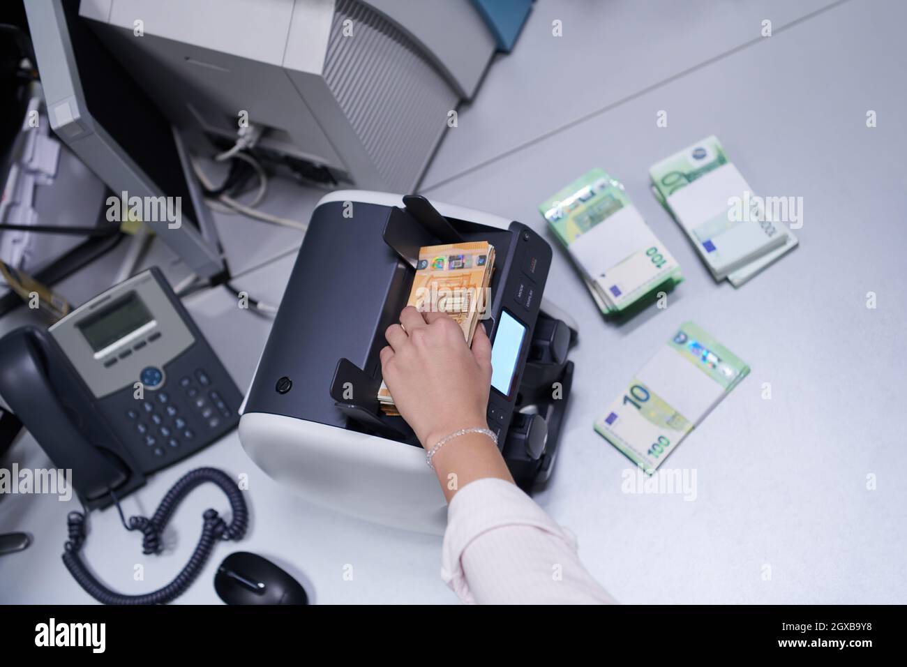 Bank employees using money counting machine while sorting and counting ...