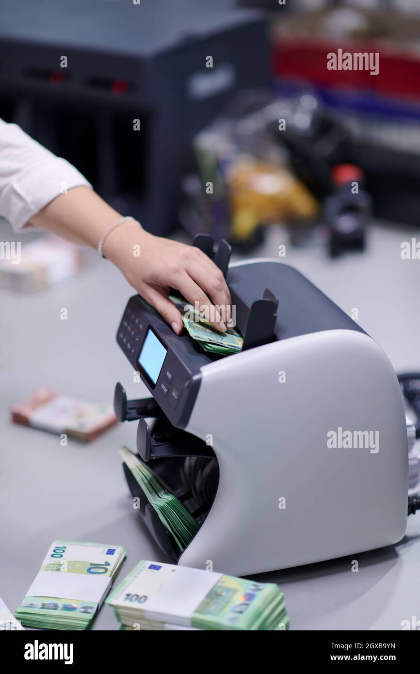 Bank employees using money counting machine while sorting and counting ...