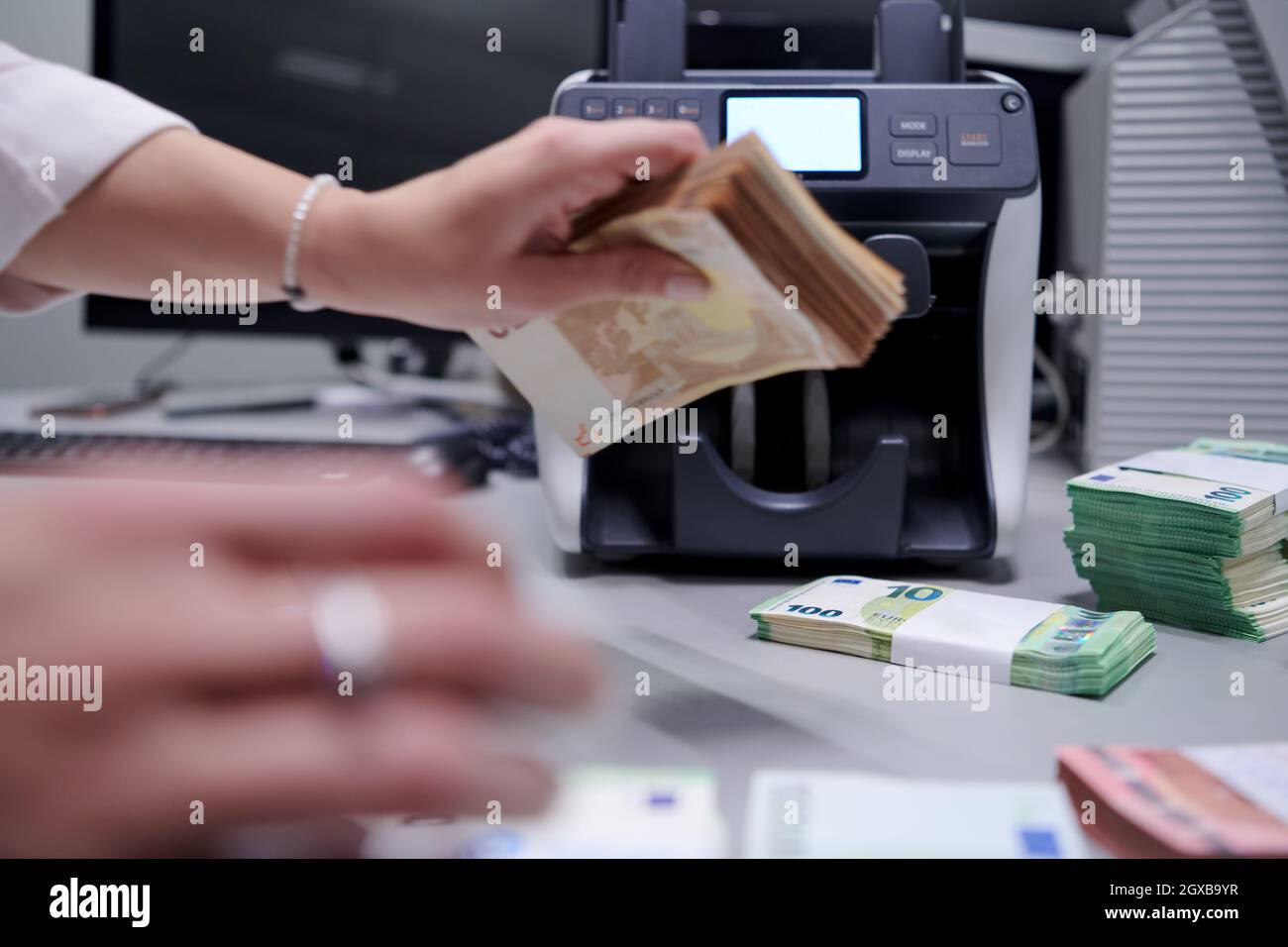 Bank employees using money counting machine while sorting and counting ...