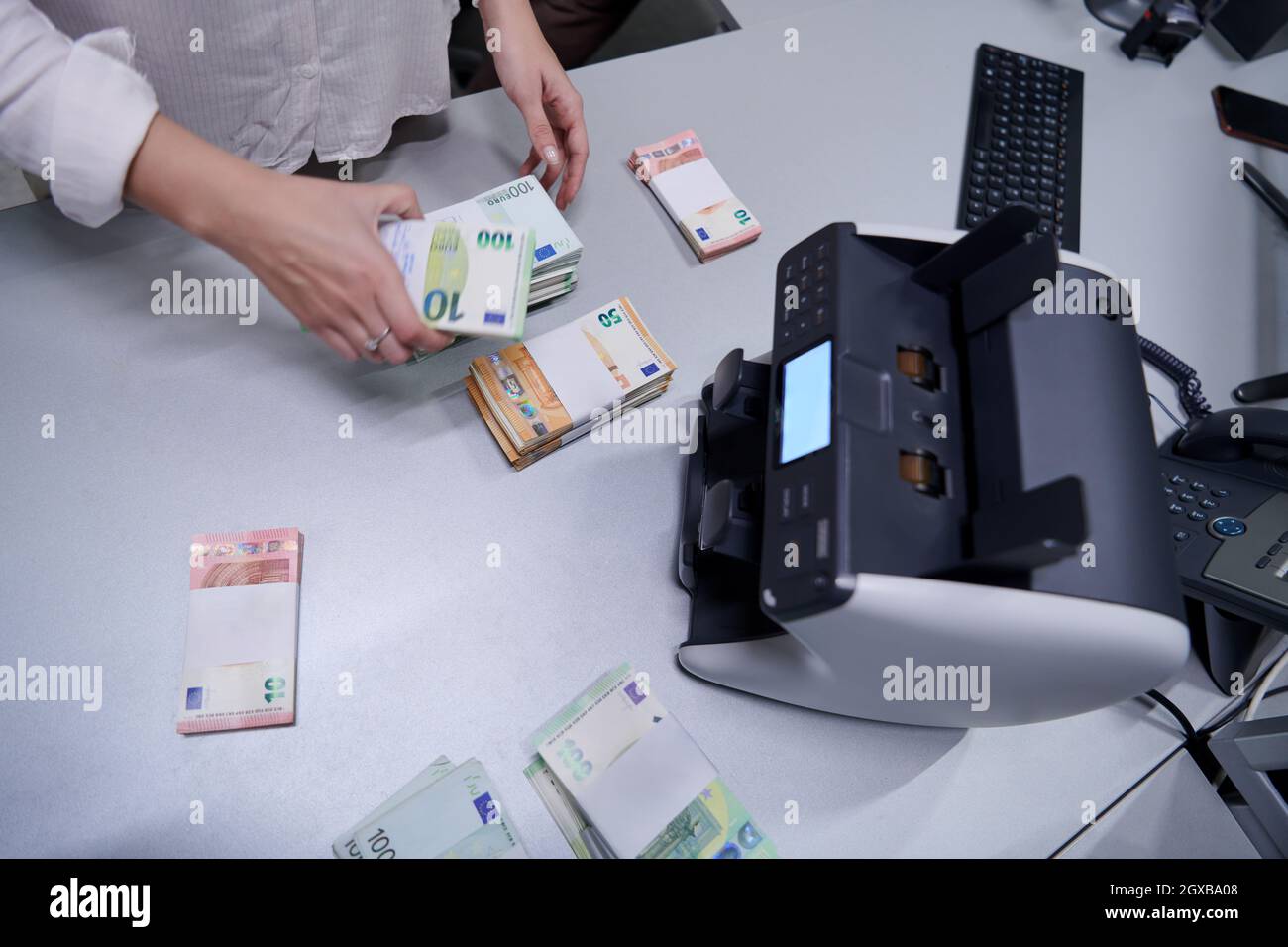 Bank employees using money counting machine while sorting and counting ...